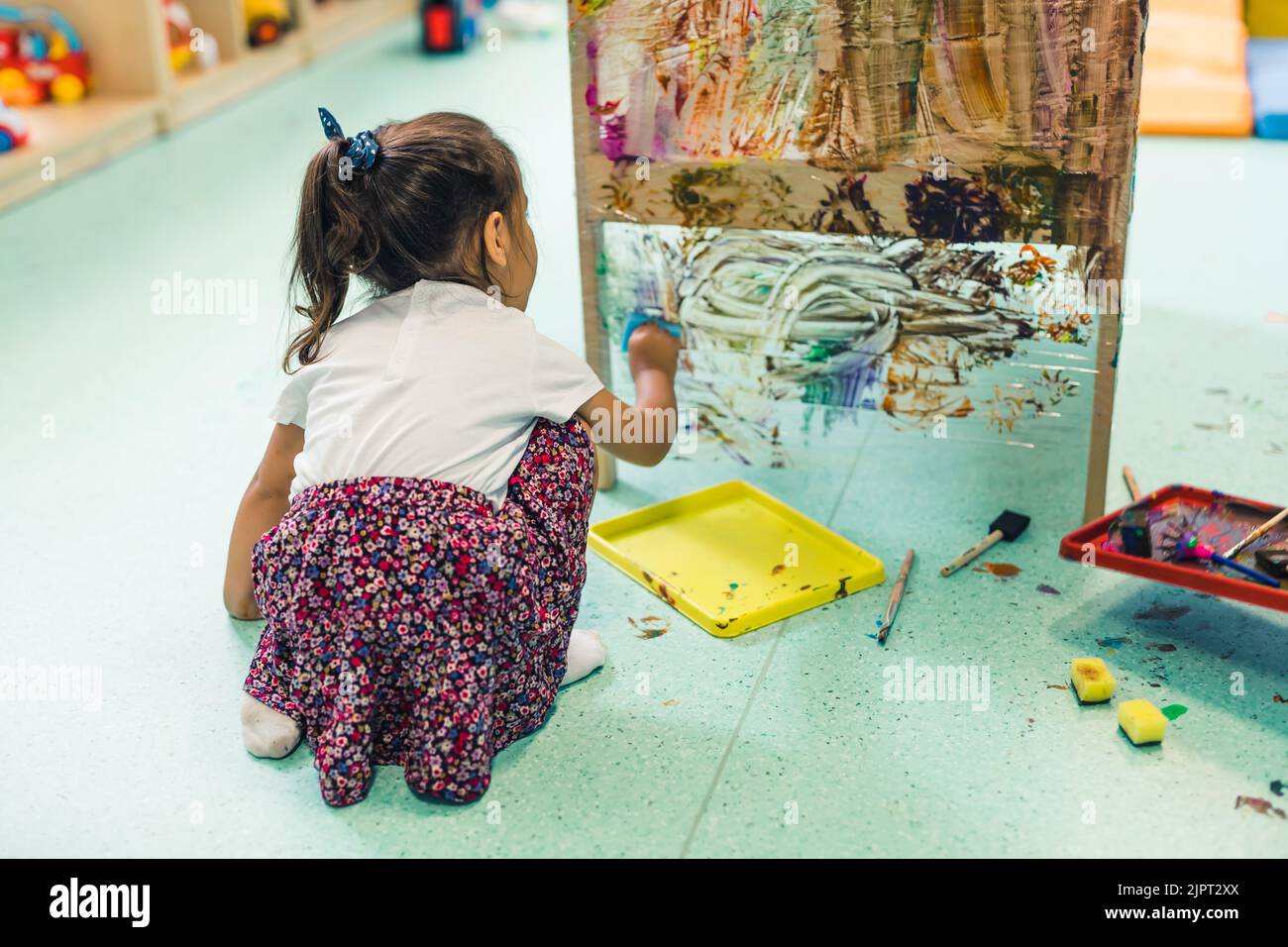a cute little girl painting on the glass in the kindergarten. High ...