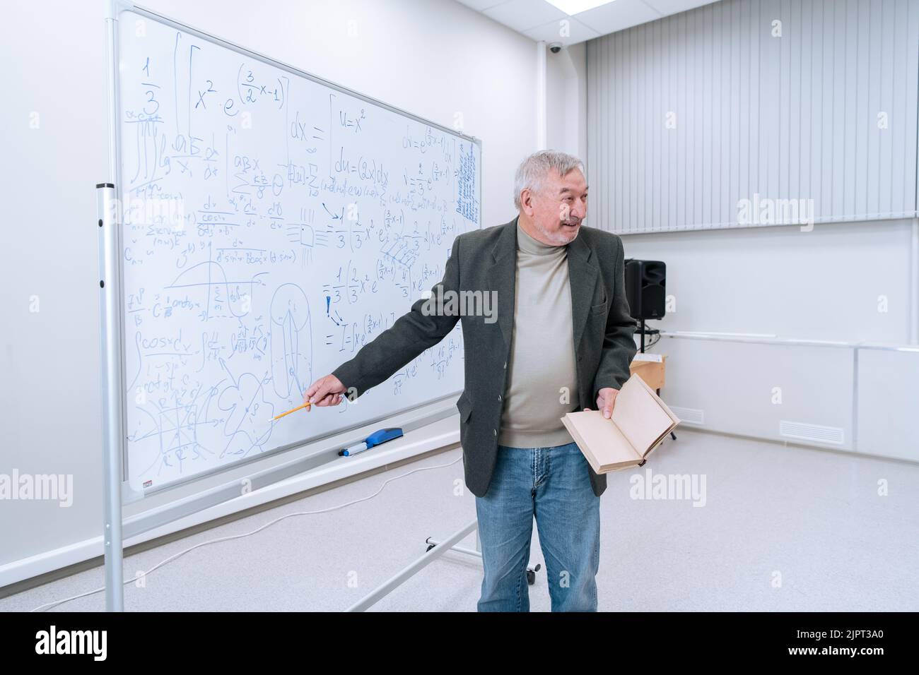 A gray-haired famous professor in a jacket and jeans shows his way of ...