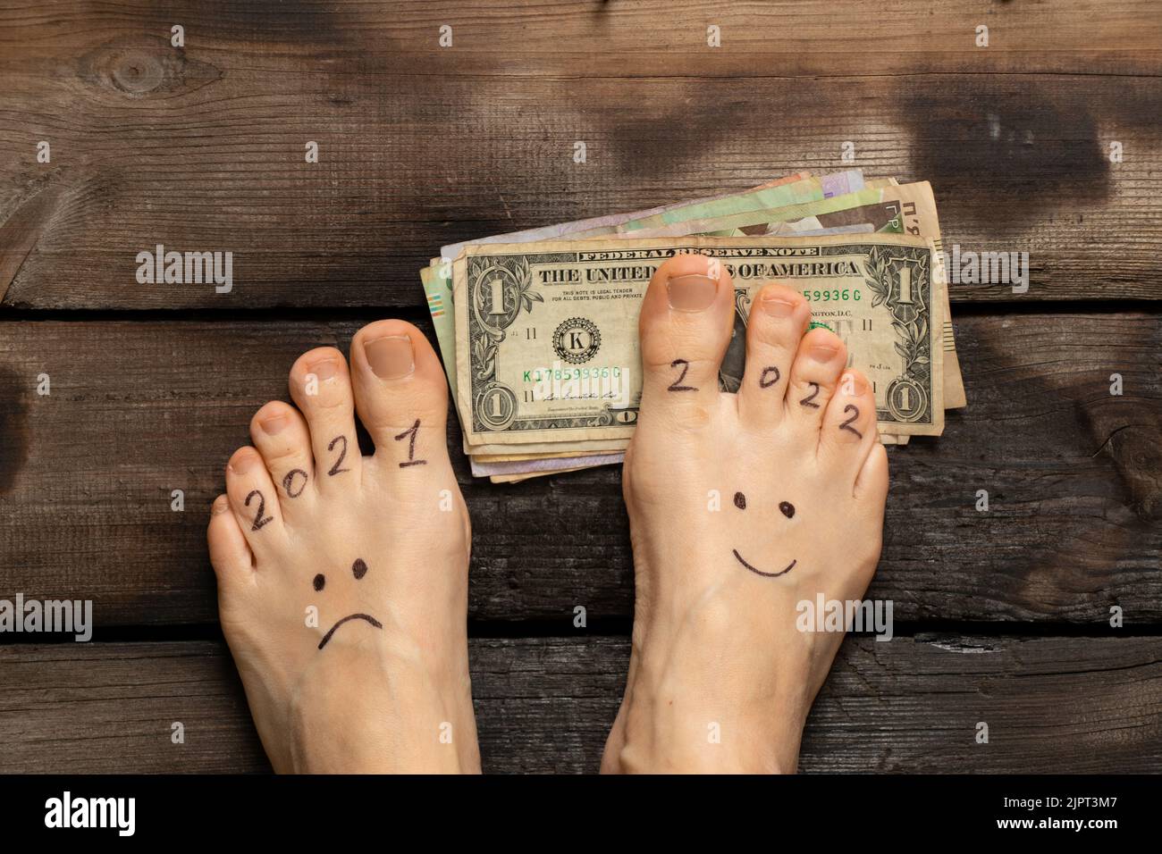 2021 and 2022 sad and joyful emoticon drawn on the legs of a girl on ...