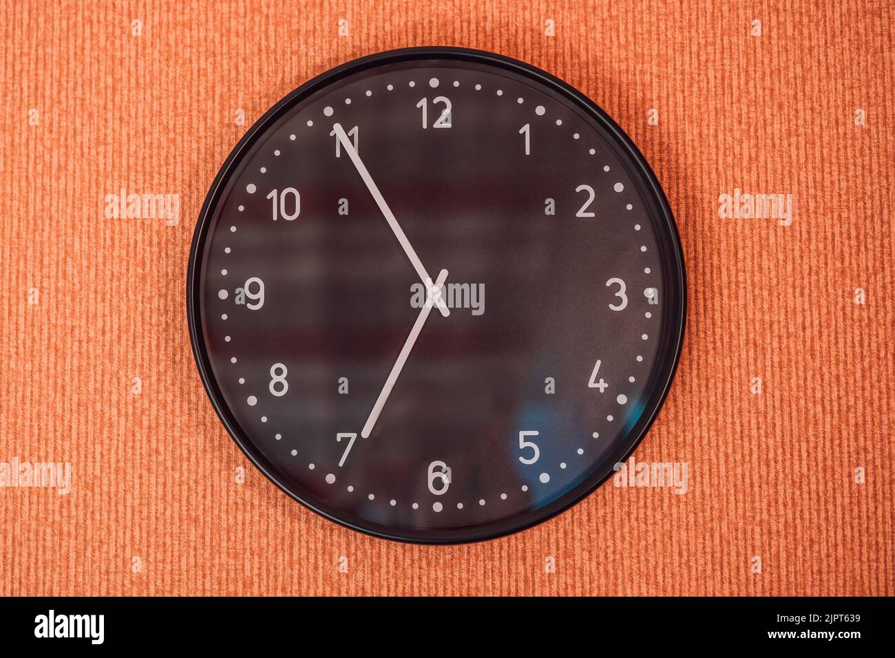 Classic black and white analog clock on red background at One o'clock ...