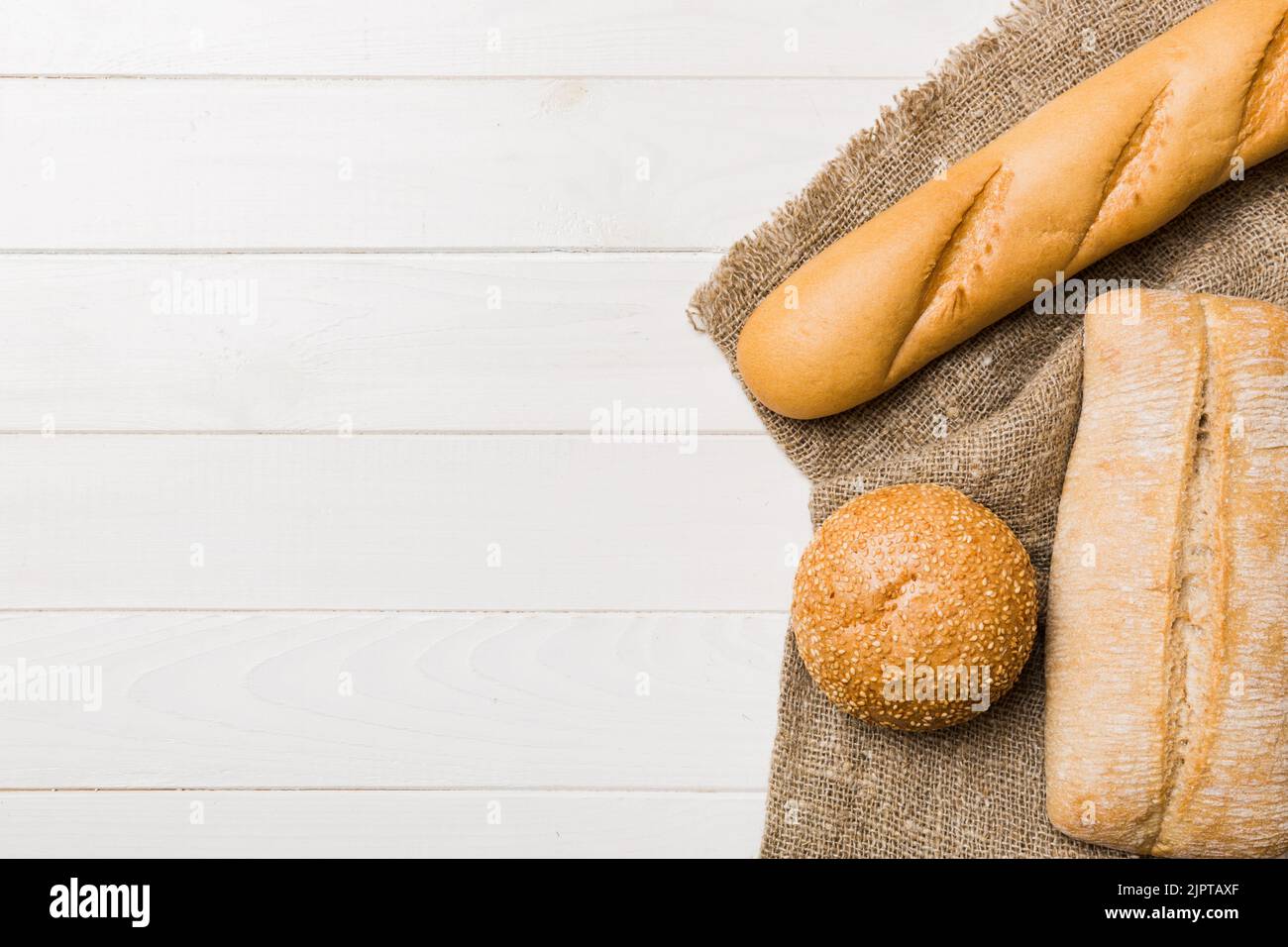 Assortment of freshly baked bread with napkin on rustic table top view ...
