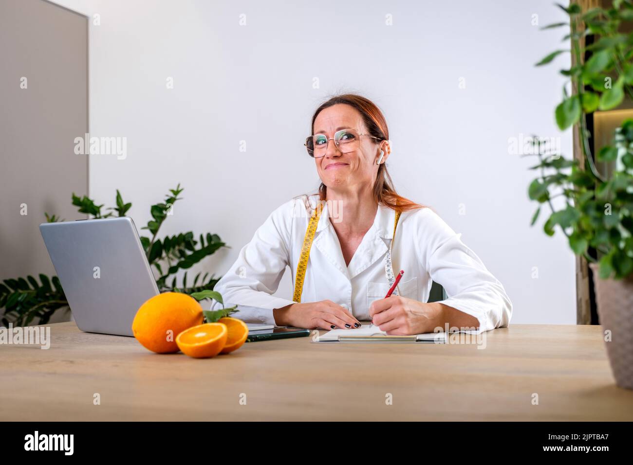 Portrait of smiling young female nutritionist in her office in medical ...