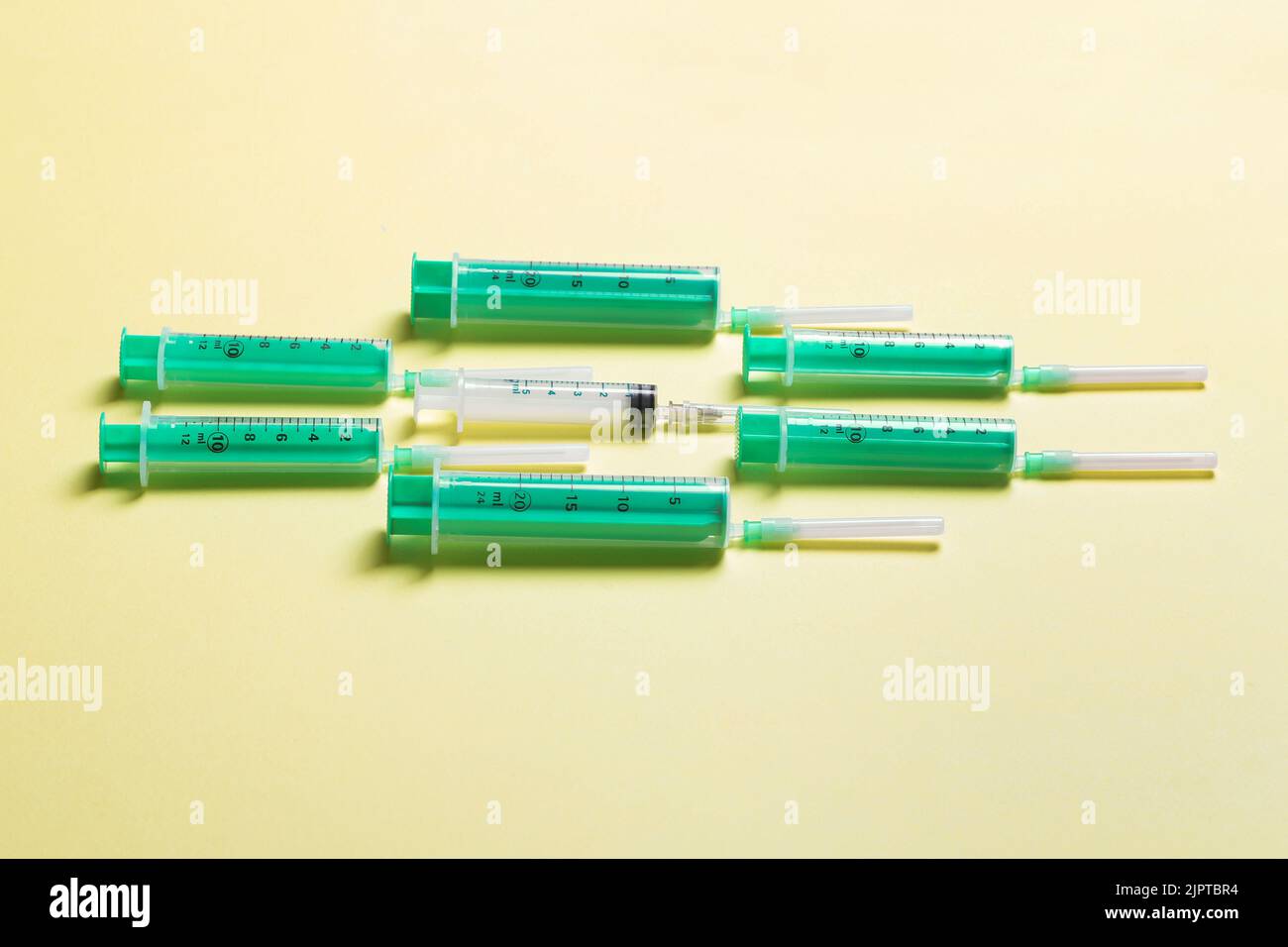 Top view of medical syringes with needles at yellow background with ...