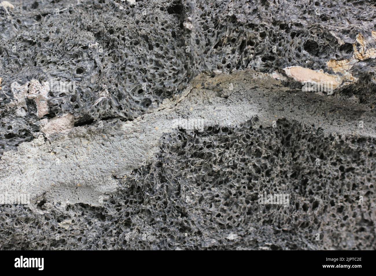 A closeup of a joint between two huge lava rocks set in a wall in black ...