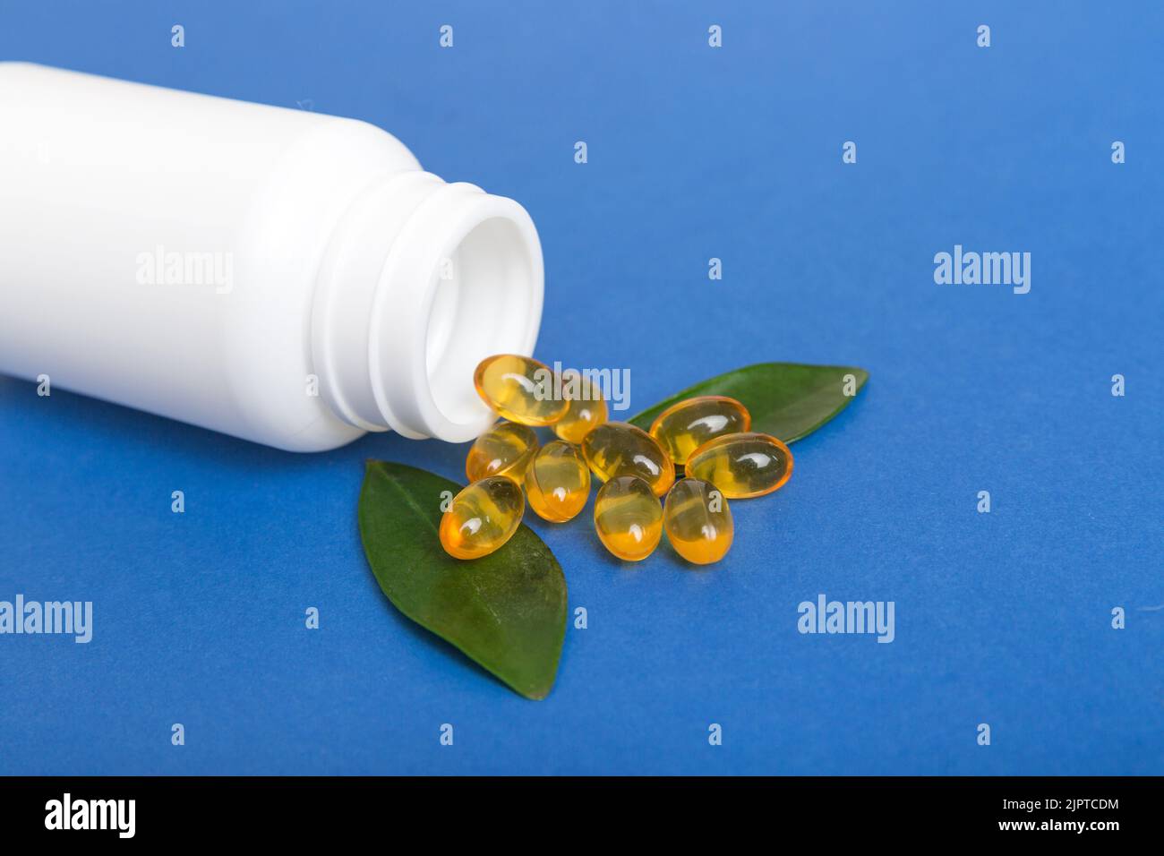 Omega-3 capsules lie in white bottle on a table background. Fish oil ...
