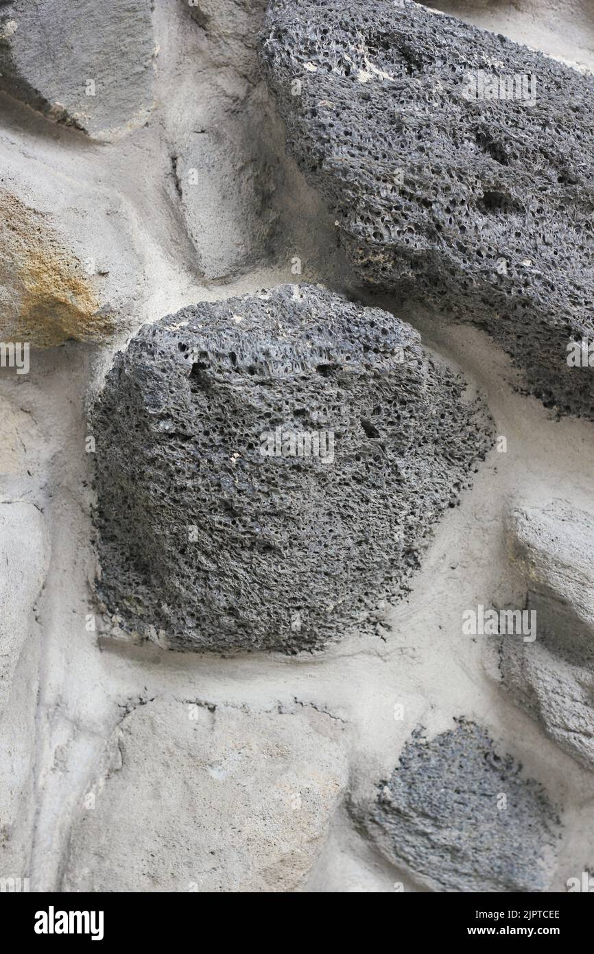 A lava rock set inside a natural stone wall Stock Photo - Alamy