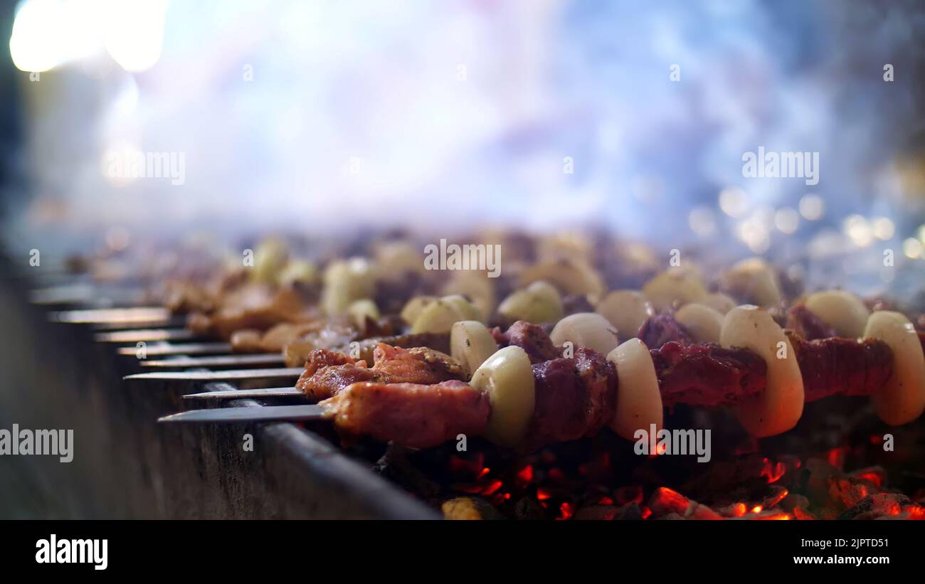 Grilled kebab cooking on metal skewer close up. Roasted meat cooked at ...