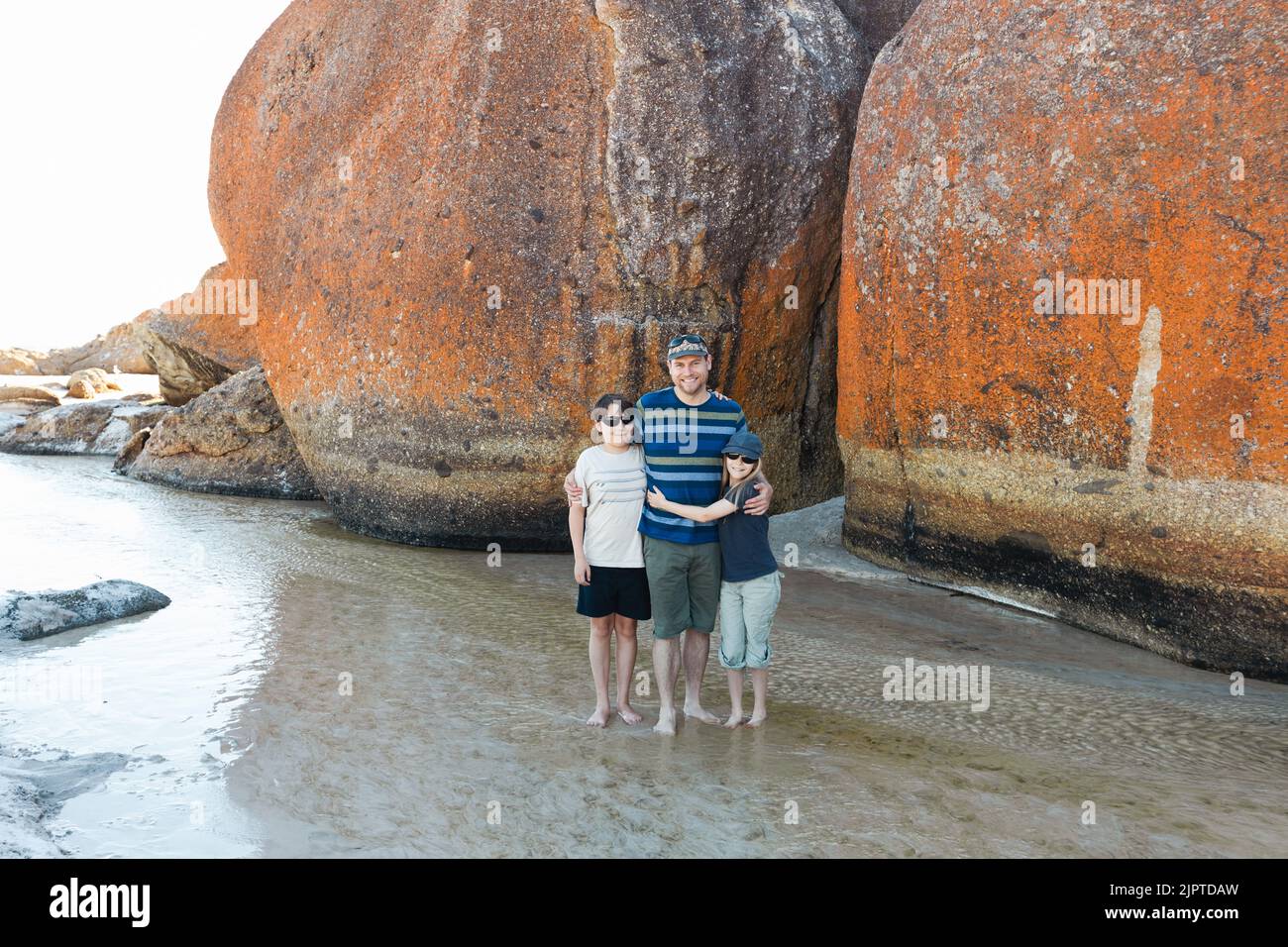 a father, daughter and son wearing sun glasses and a hat next to ...