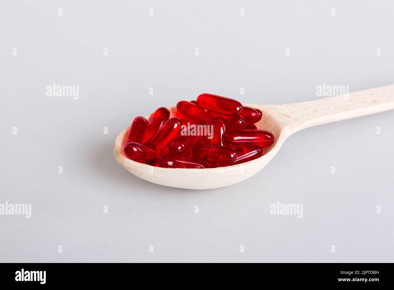 Vitamin capsules in a spoon on a colored background. Pills served as a ...