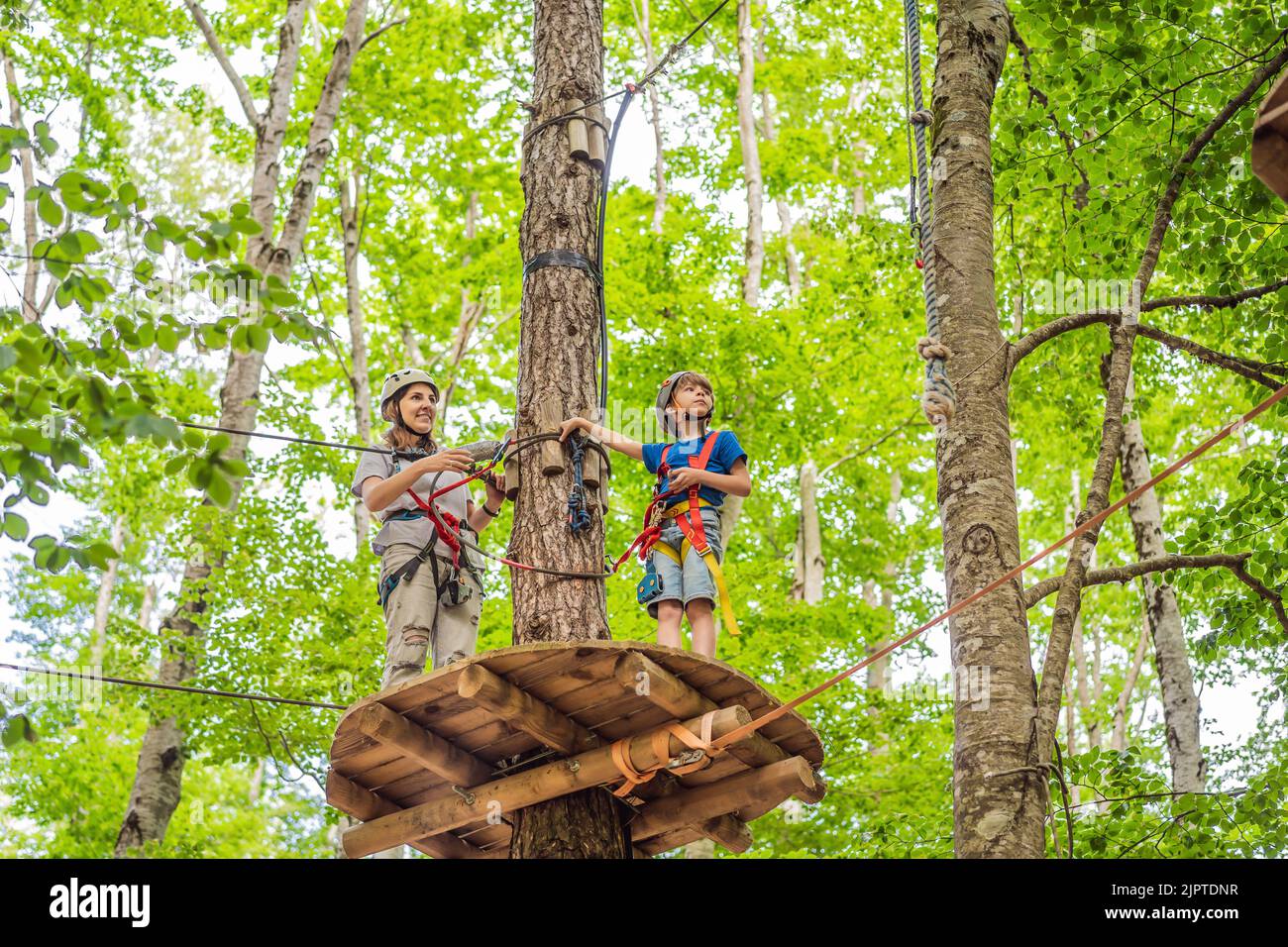 Mother and son climbing in extreme road trolley zipline in forest on ...