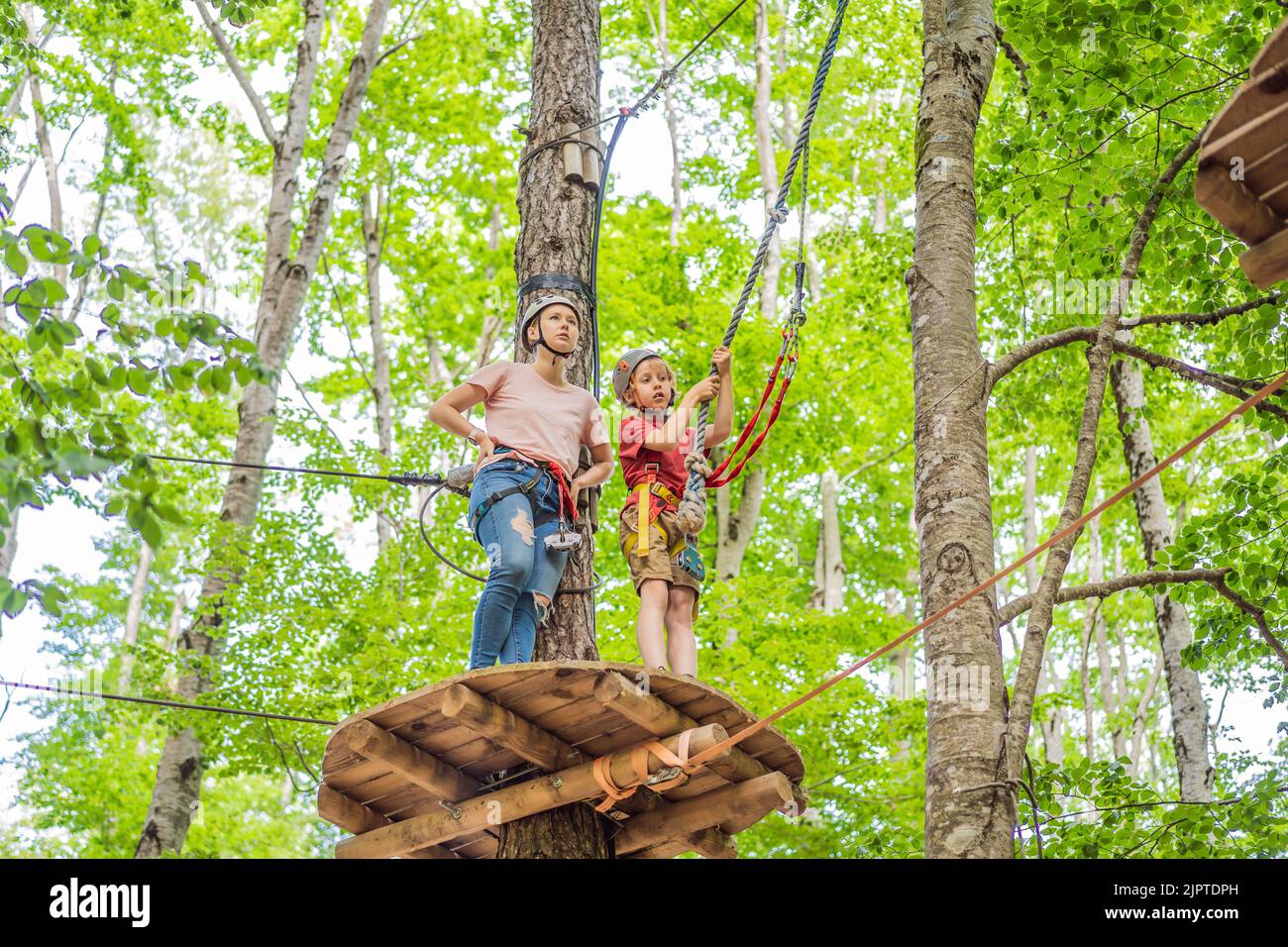 Mother and son climbing in extreme road trolley zipline in forest on ...