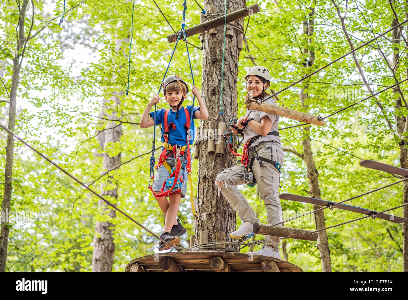 Mother and son climbing in extreme road trolley zipline in forest on ...