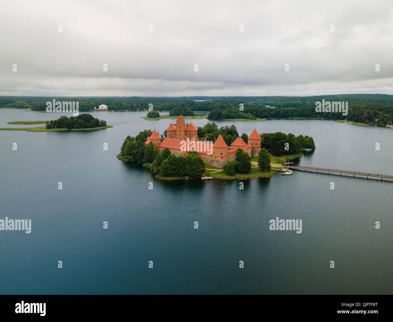 An aerial shot of the Trakai castle surrounded by green trees over the ...