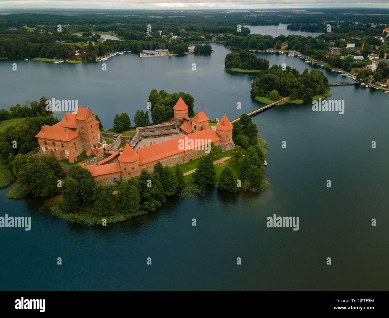 An aerial shot of the Trakai castle surrounded by green trees over the ...