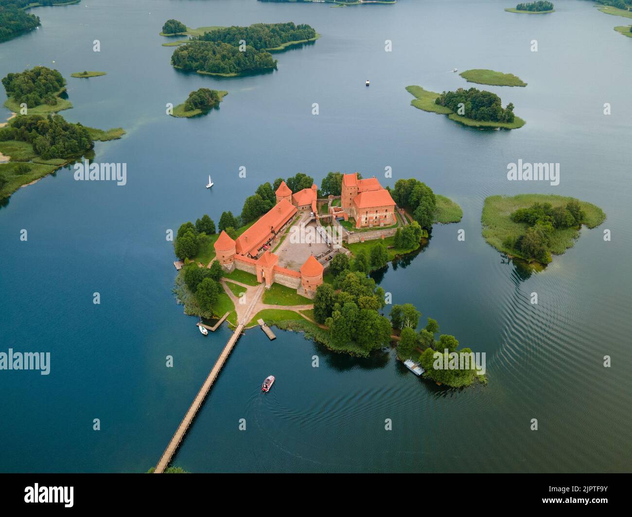 An aerial shot of the Trakai castle surrounded by green trees over the ...