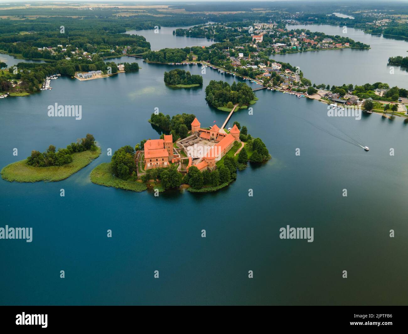 An aerial shot of the Trakai castle surrounded by trees over the Galves ...