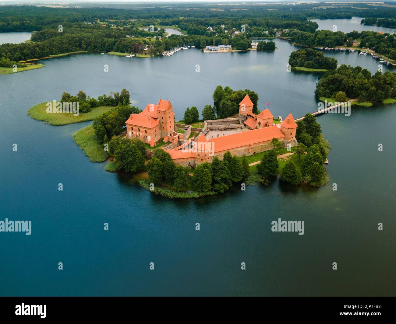 An aerial shot of the Trakai castle surrounded by green trees over the ...