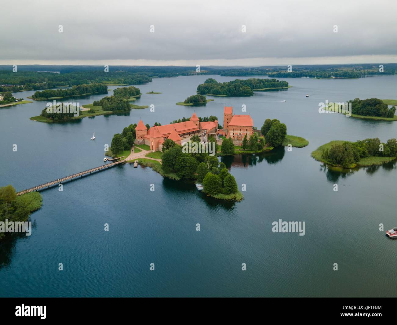 An aerial shot of the Trakai castle surrounded by green trees over the ...
