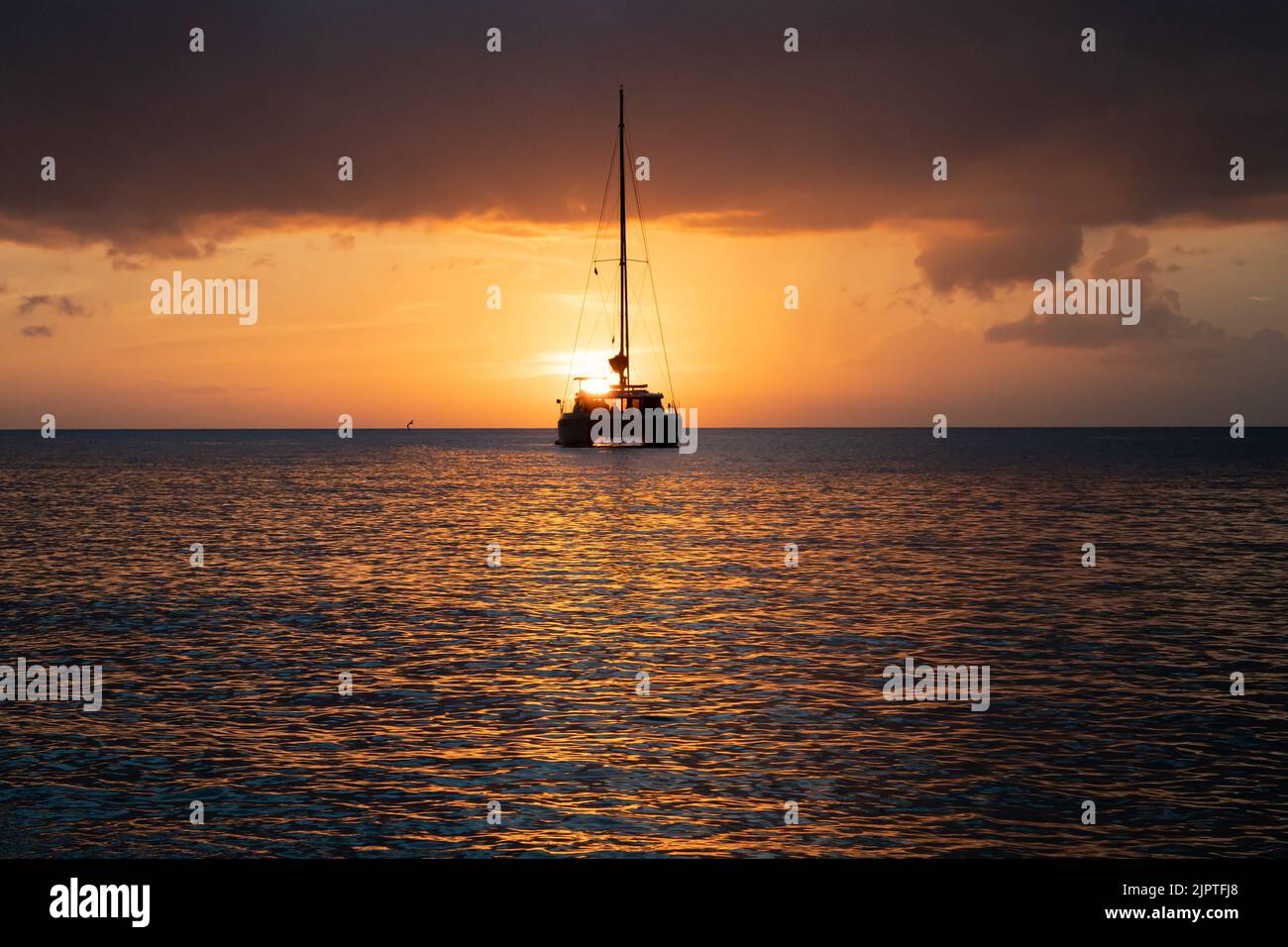 Sailboat sailing off into the setting sun on the ocean horizon Stock ...