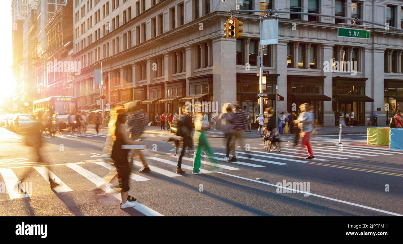 Sunlight shining on people in motion walking across a busy street ...