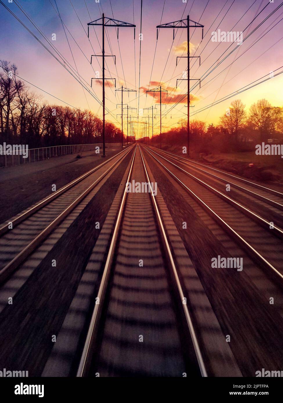 Traveling on railroad train tracks into the setting sunlight on the ...