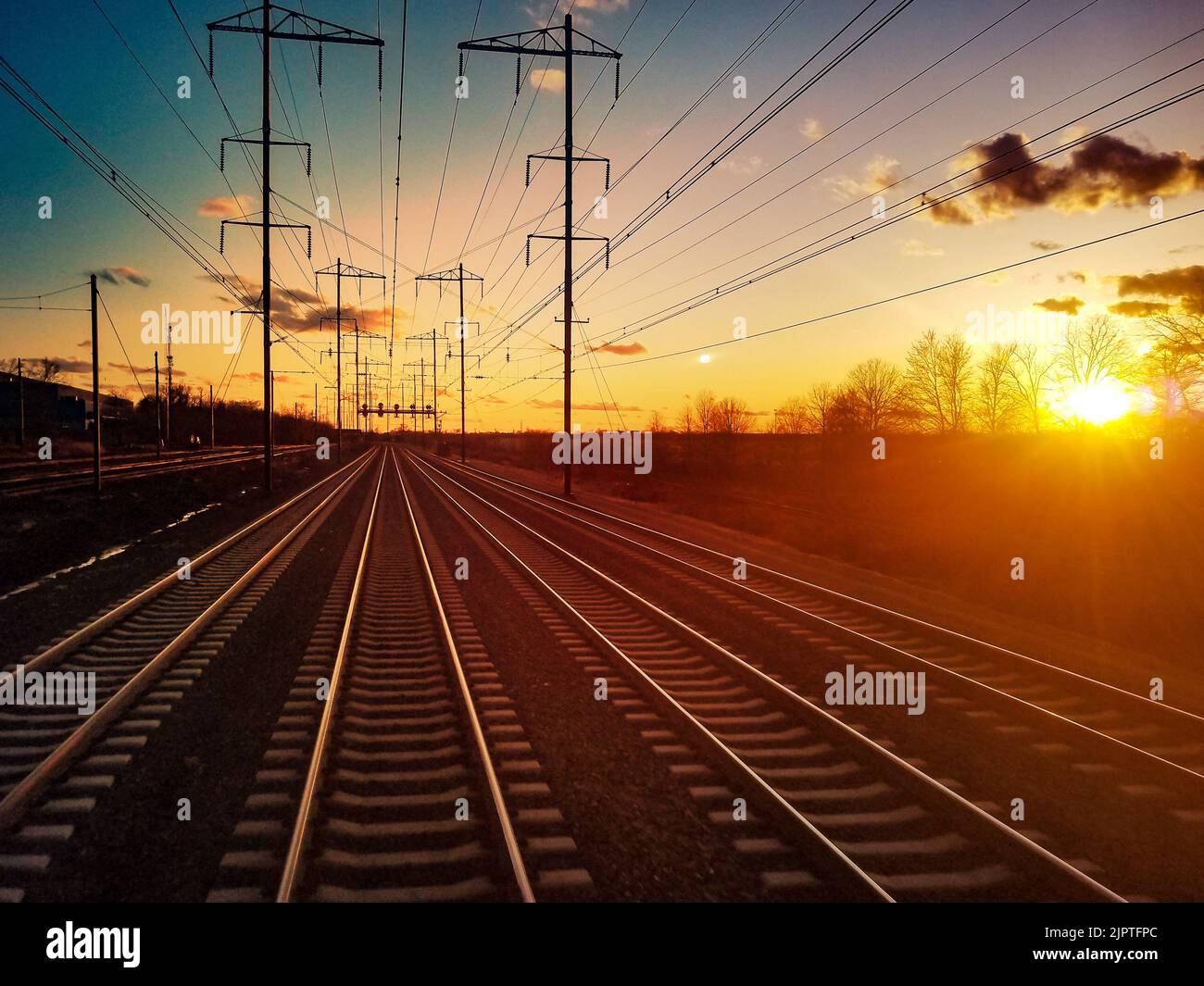 Train tracks headed into the distant horizon with the colorful light of ...