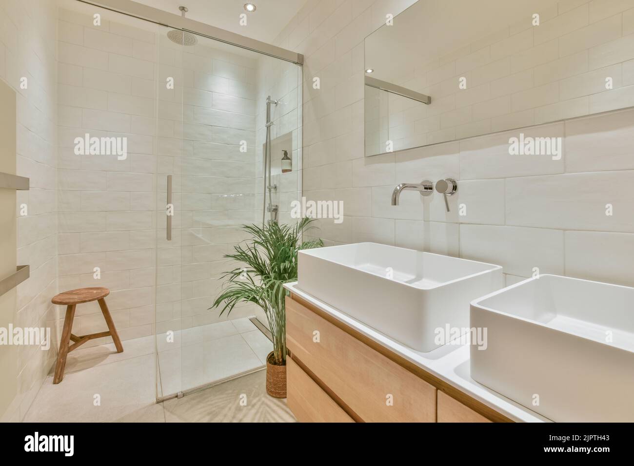 Fragment of interior of modern white bathroom with wooden cabinet under ...