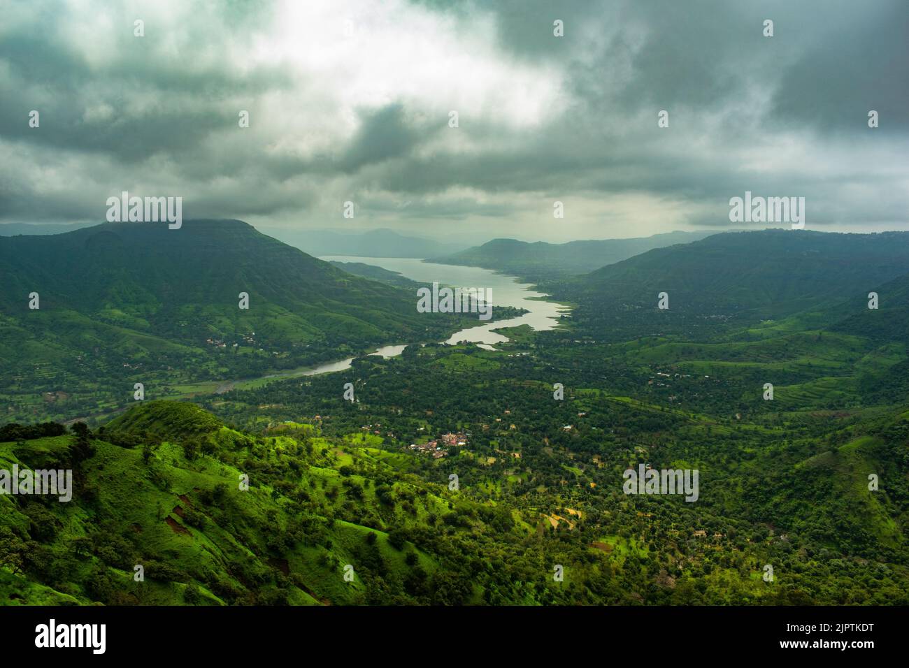 A scenic view of river and trees on a mountain under blue sky ...
