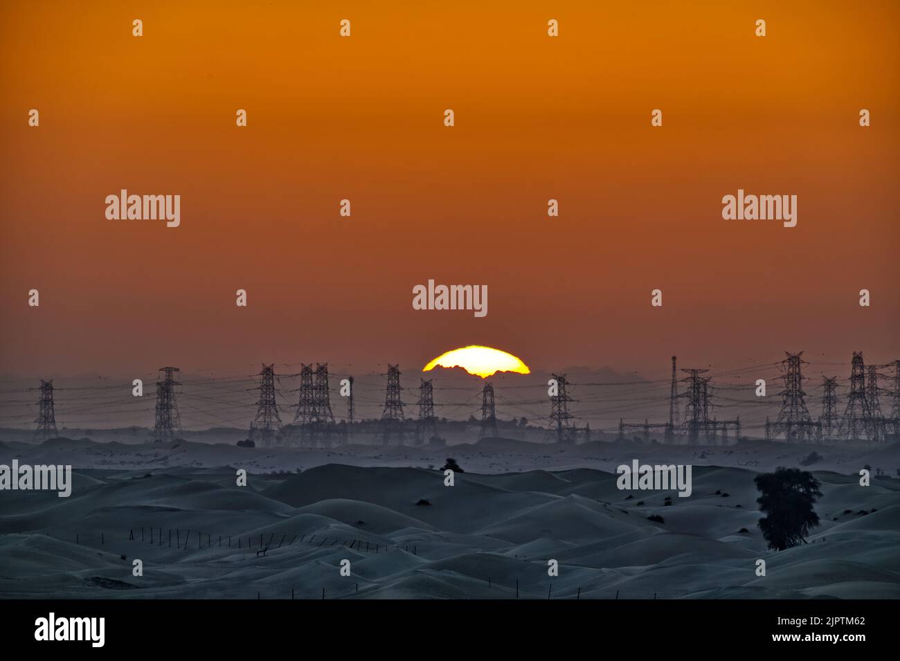 The sun over rows of power towers on a landscape during sunset Stock ...