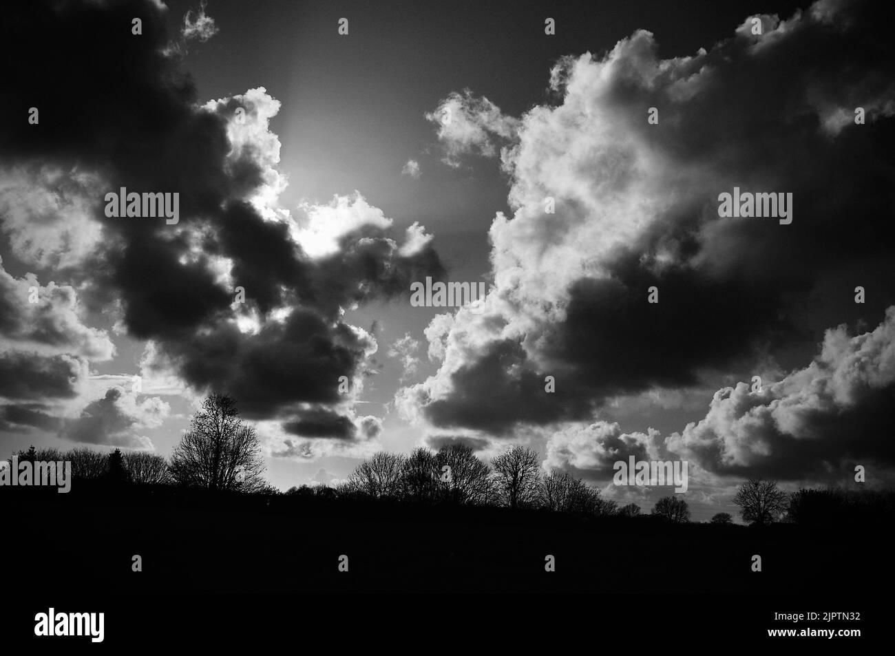 Cumulo Nimbus clouds lit by setting sun pictured in black and white in Normandy France in April ...