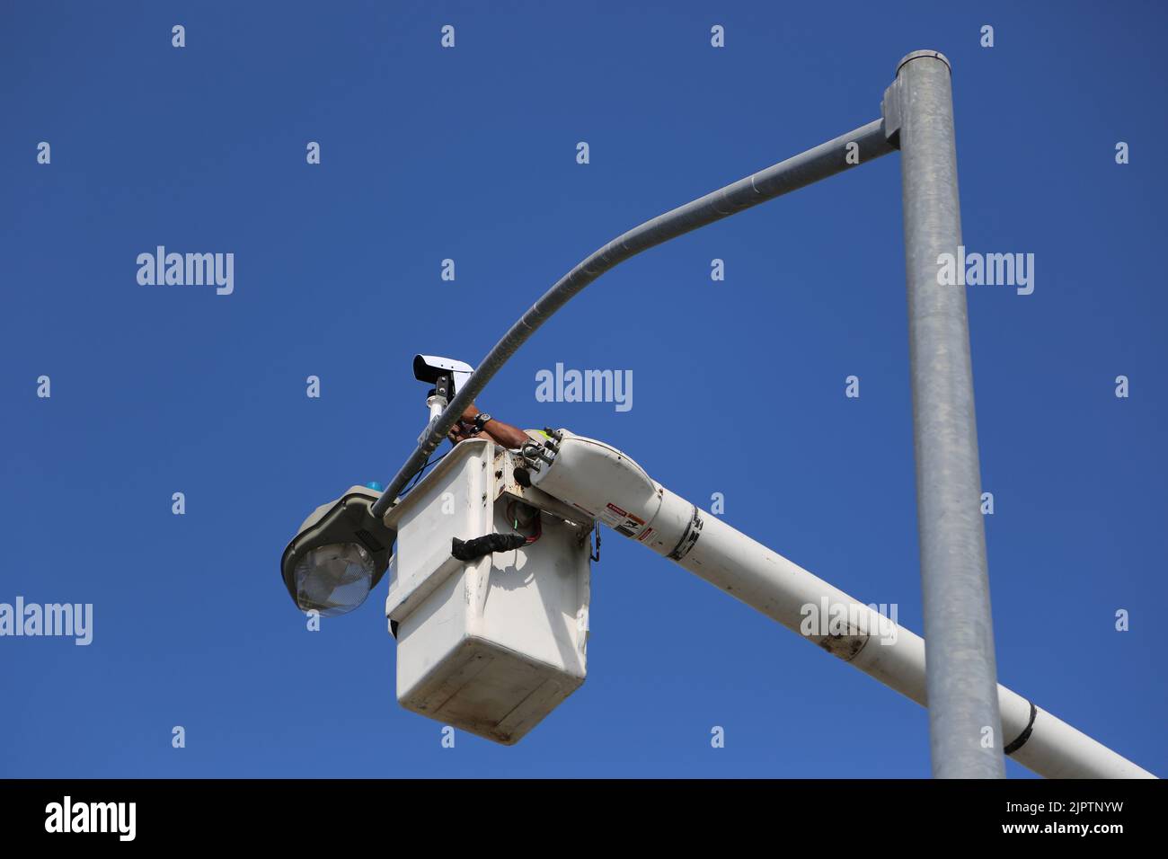 A closeup of a worker connecting a security camera on top of an old ...