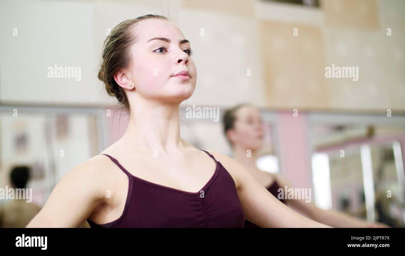 in dancing hall, Young ballerina in purple leotard performs a certain ...