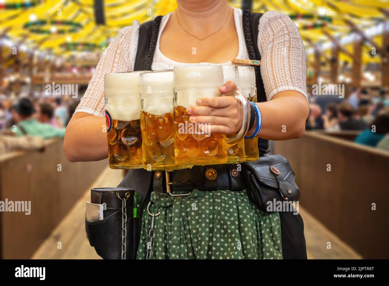 Oktoberfest, Munich. Waiter in traditional Bavarian costume serving beers, close up view ...