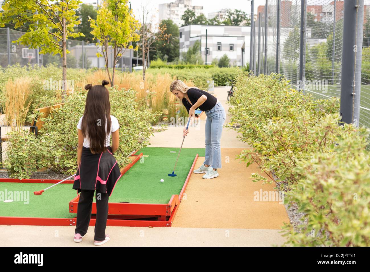 Miniature golf outdoor. Little caucasian girl golfing in the mini golf ...