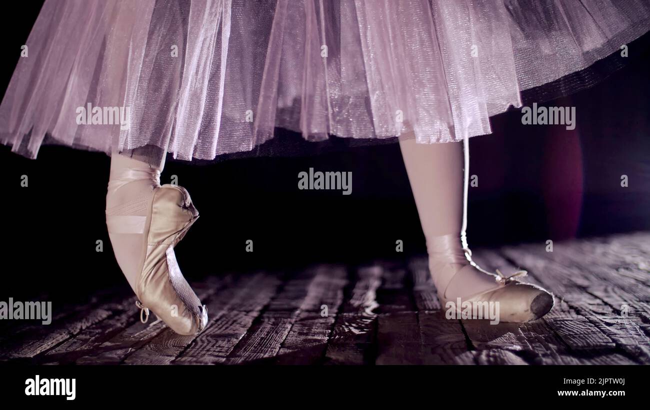 close up, in rays of spotlight, on stage of old theater hall. ballerina ...