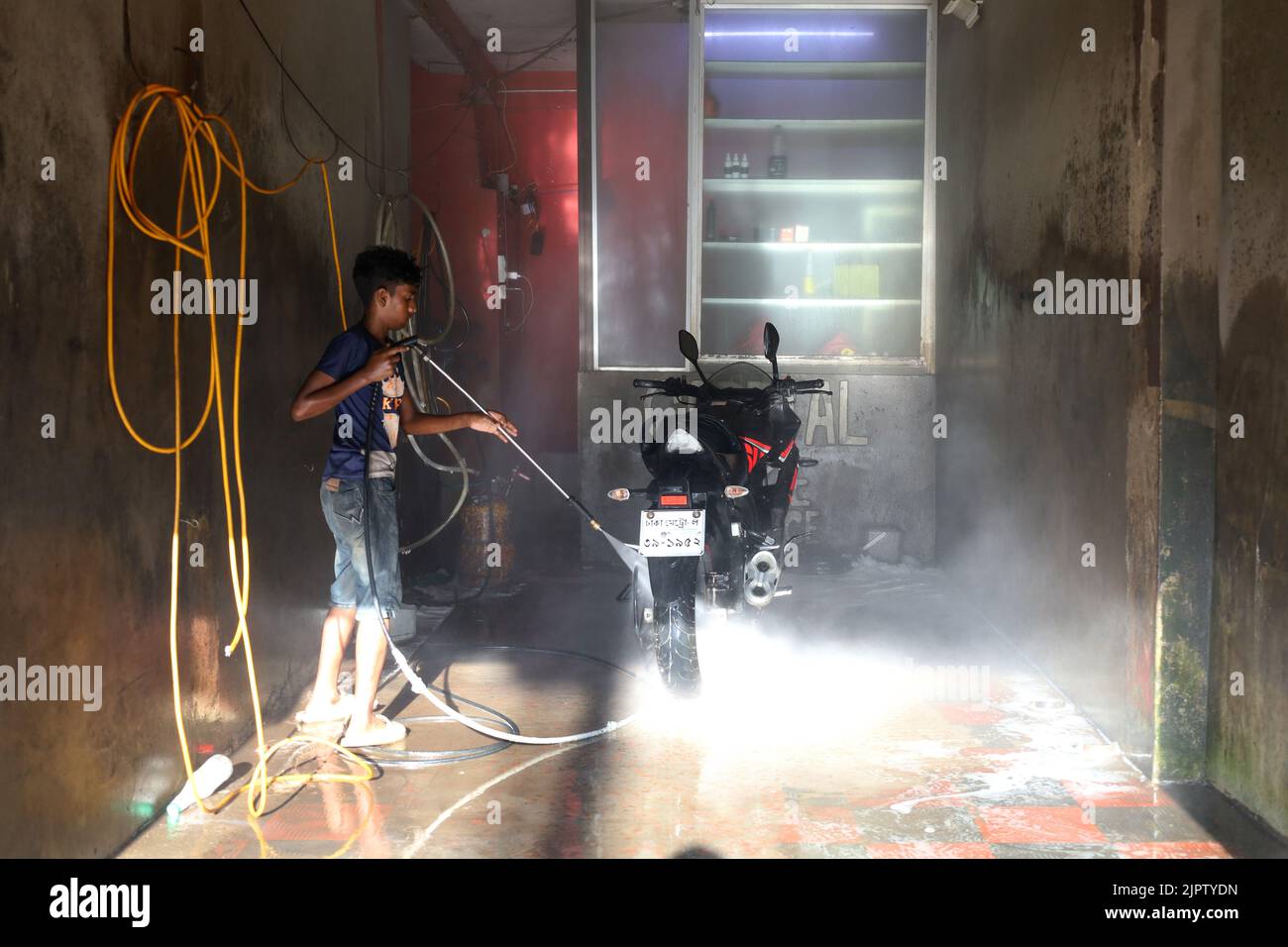 Dhaka, Dhaka, Bangladesh. 20th Aug, 2022. A boy washes a bike at a bike wash shop in Dhaka ...