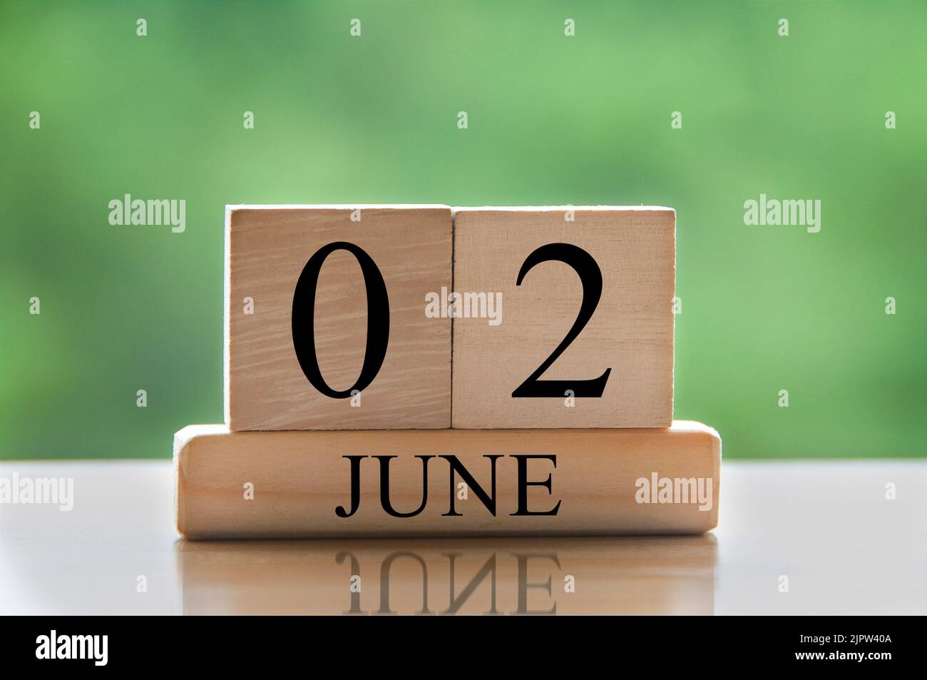 June 2 calendar date text on wooden blocks with blurred nature ...