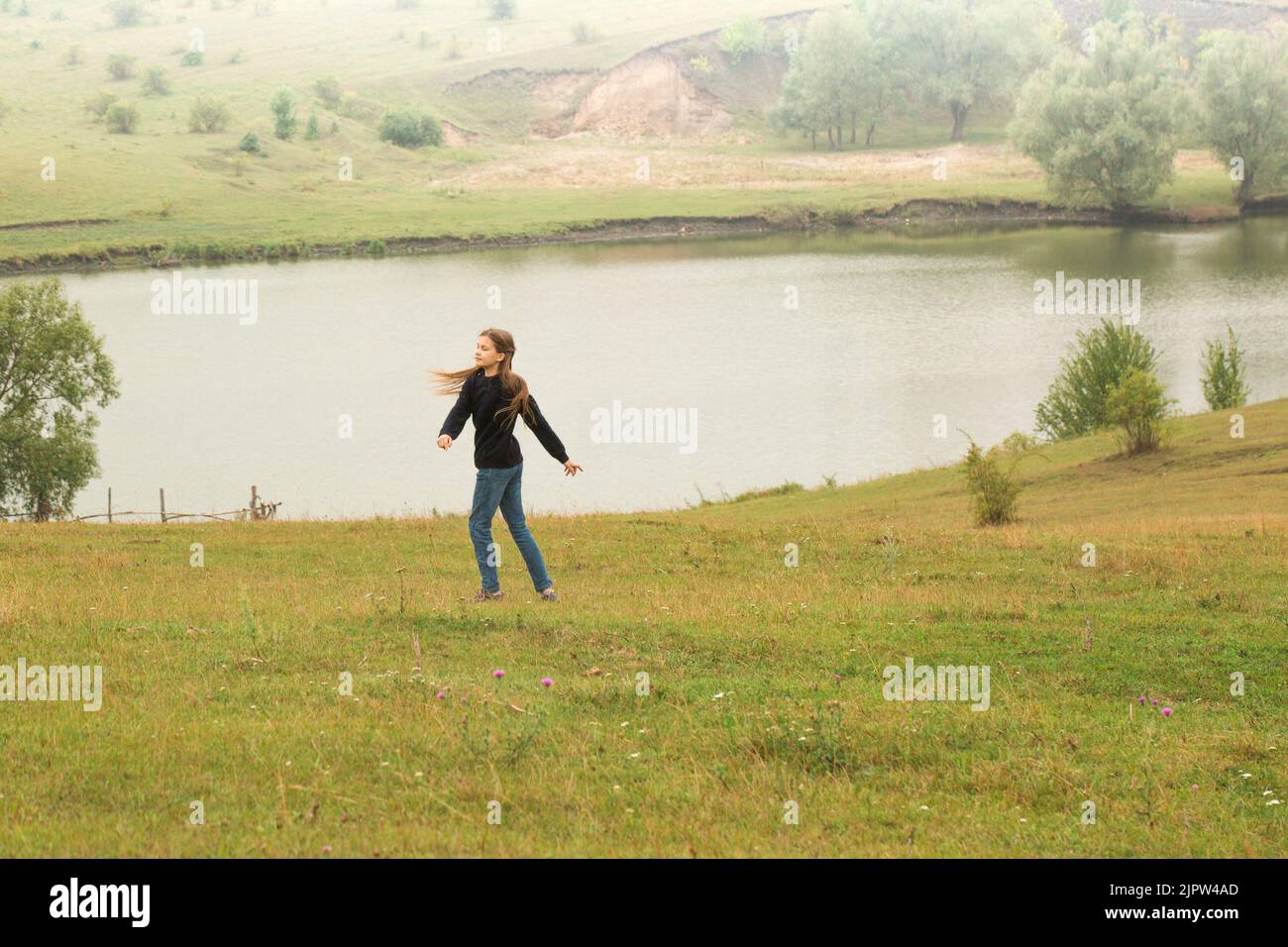 A teenage girl is having fun in a clearing by the lake Stock Photo - Alamy