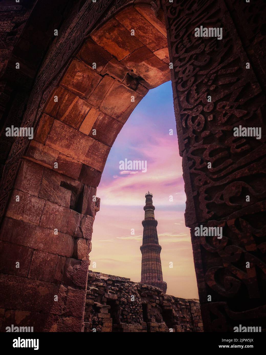 A vertical shot of the Qutb Minar complex from the arch at sunset Stock ...