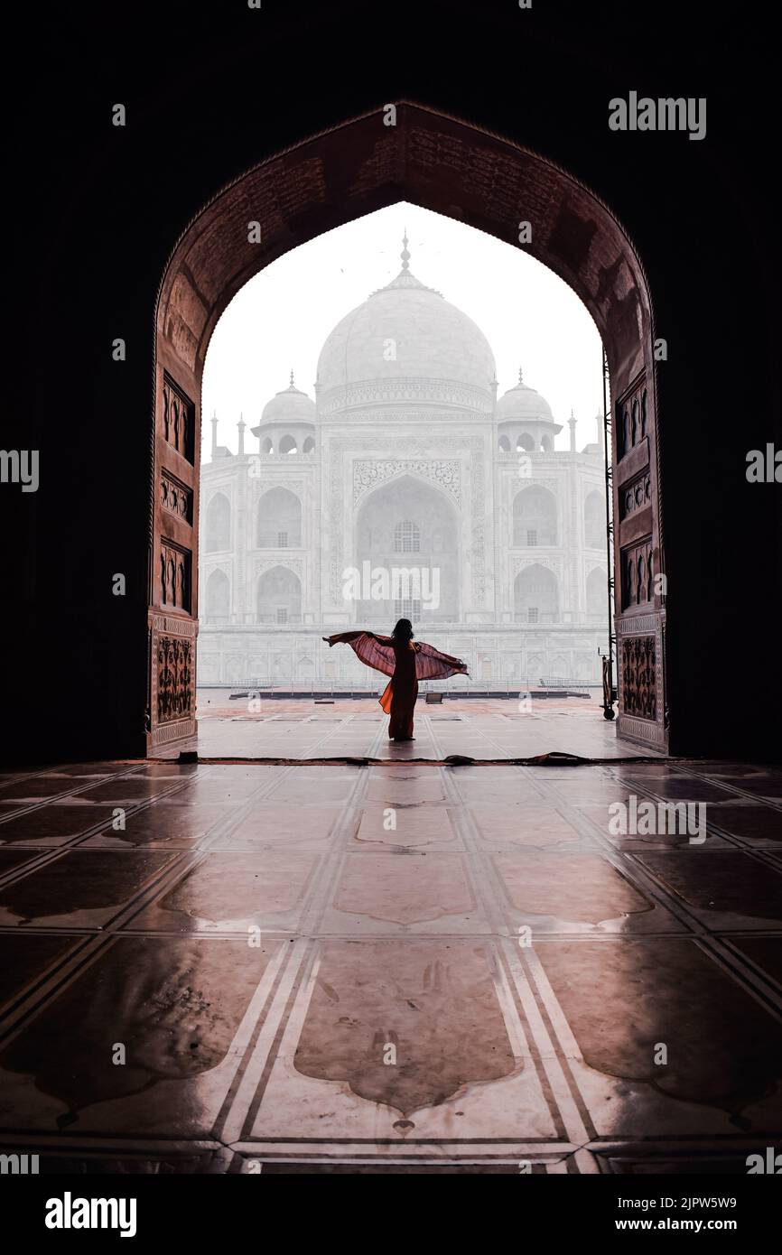 A vertical shot of a female dancing on the background of beautiful Taj ...