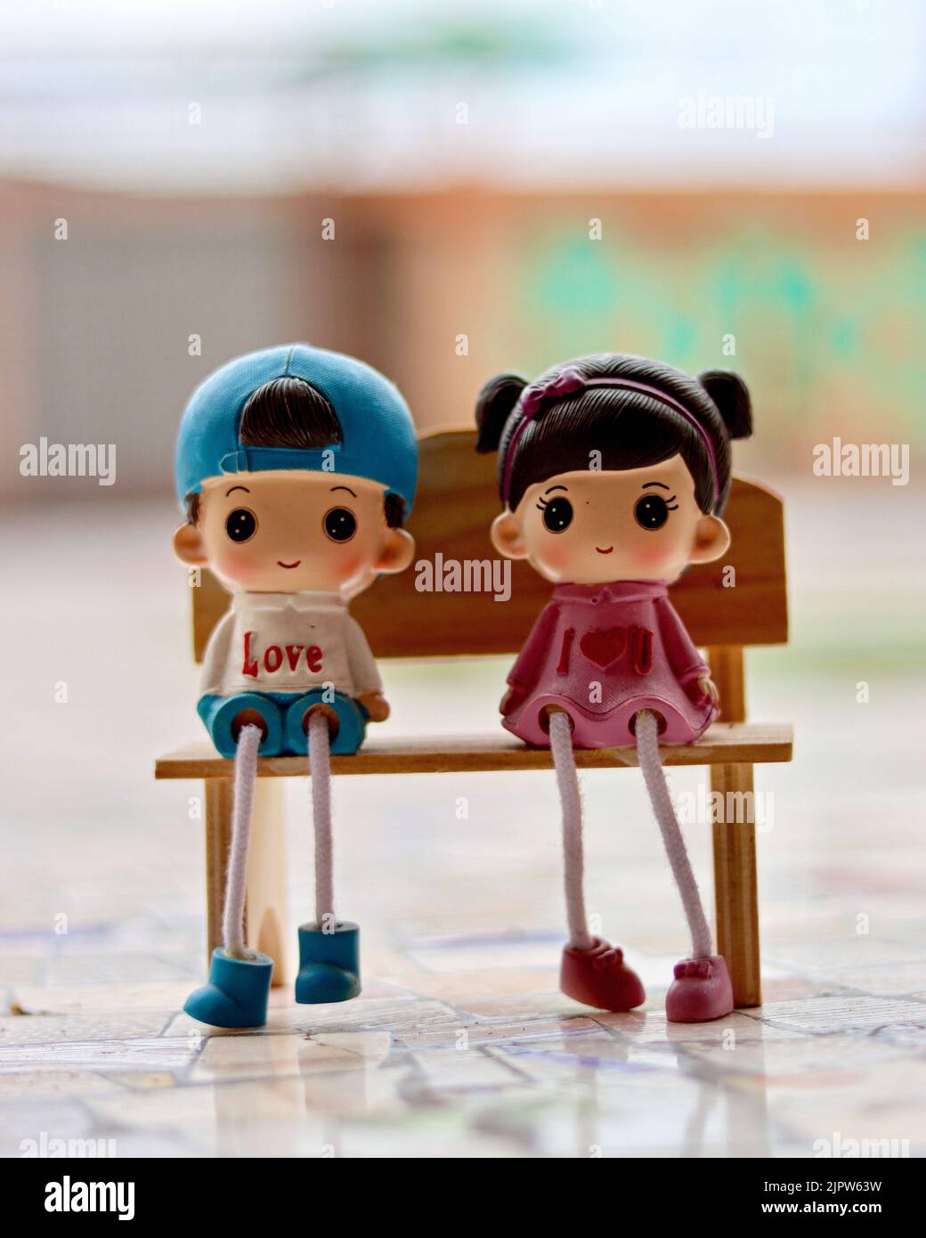 A vertical closeup shot of two small figures of girl and boy sitting on ...