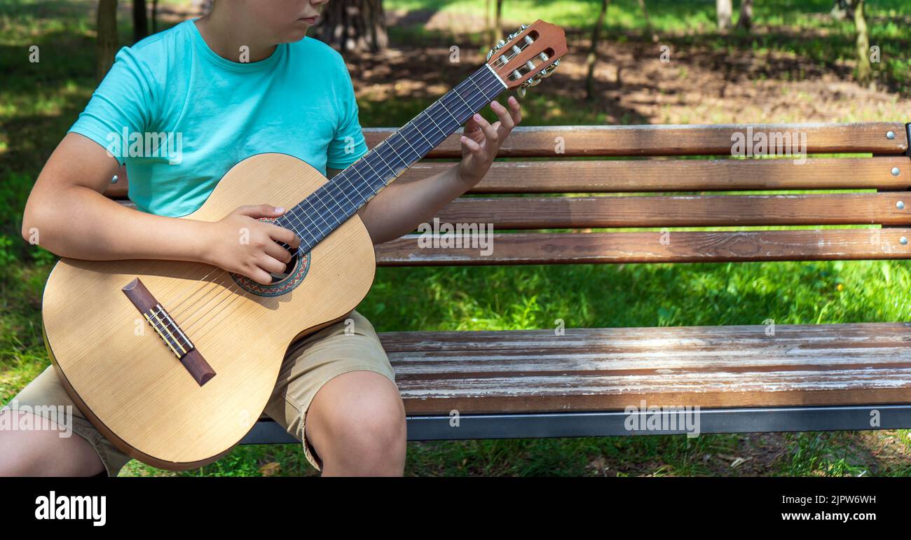 The young man plays hands and on a classic acoustic wooden guitar on ...