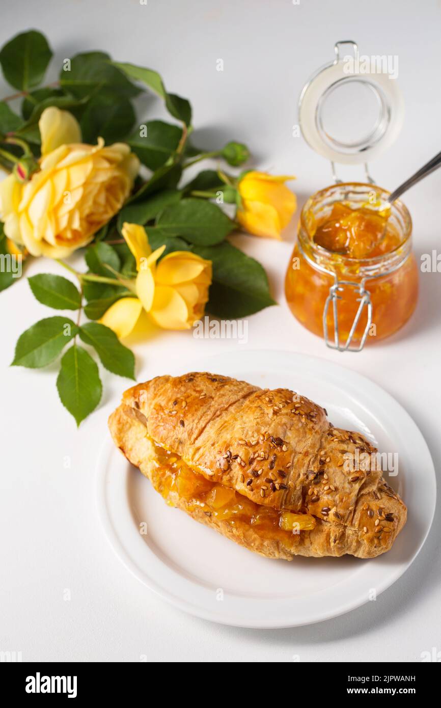 Delicious croissant with orange jam and yellow roses Stock Photo - Alamy