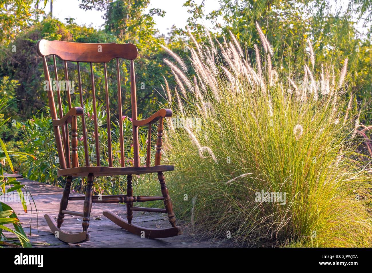 Empty rocking chair in garden at summer sunset Stock Photo - Alamy