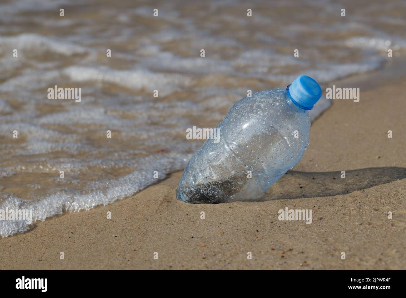 Blue plastic bottle on sea coast, pollution ecosystem planet save ...