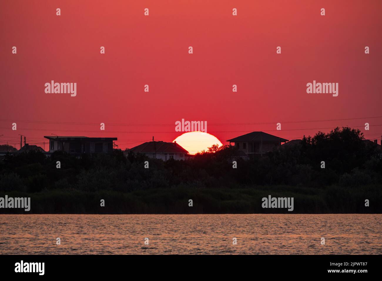 The sun goes down over a lake. Dramatic Sunset Sky Stock Photo - Alamy