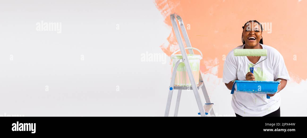 Banner smiling african american woman painting interior wall of home ...