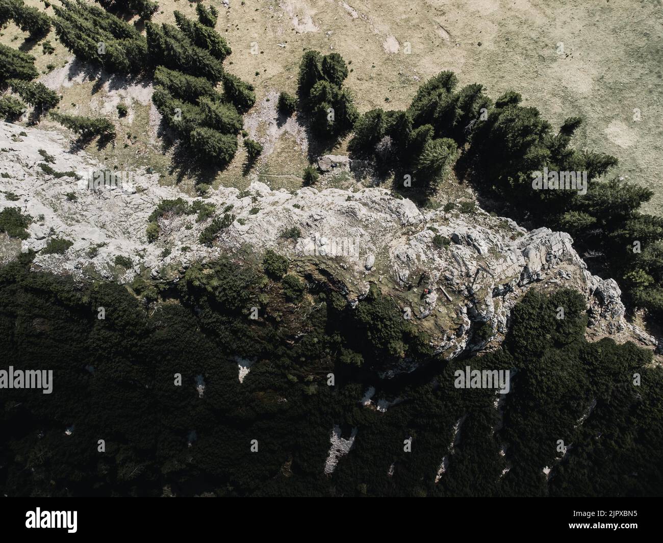 An aerial view over a rocky cliff covered with greenery growth and ...