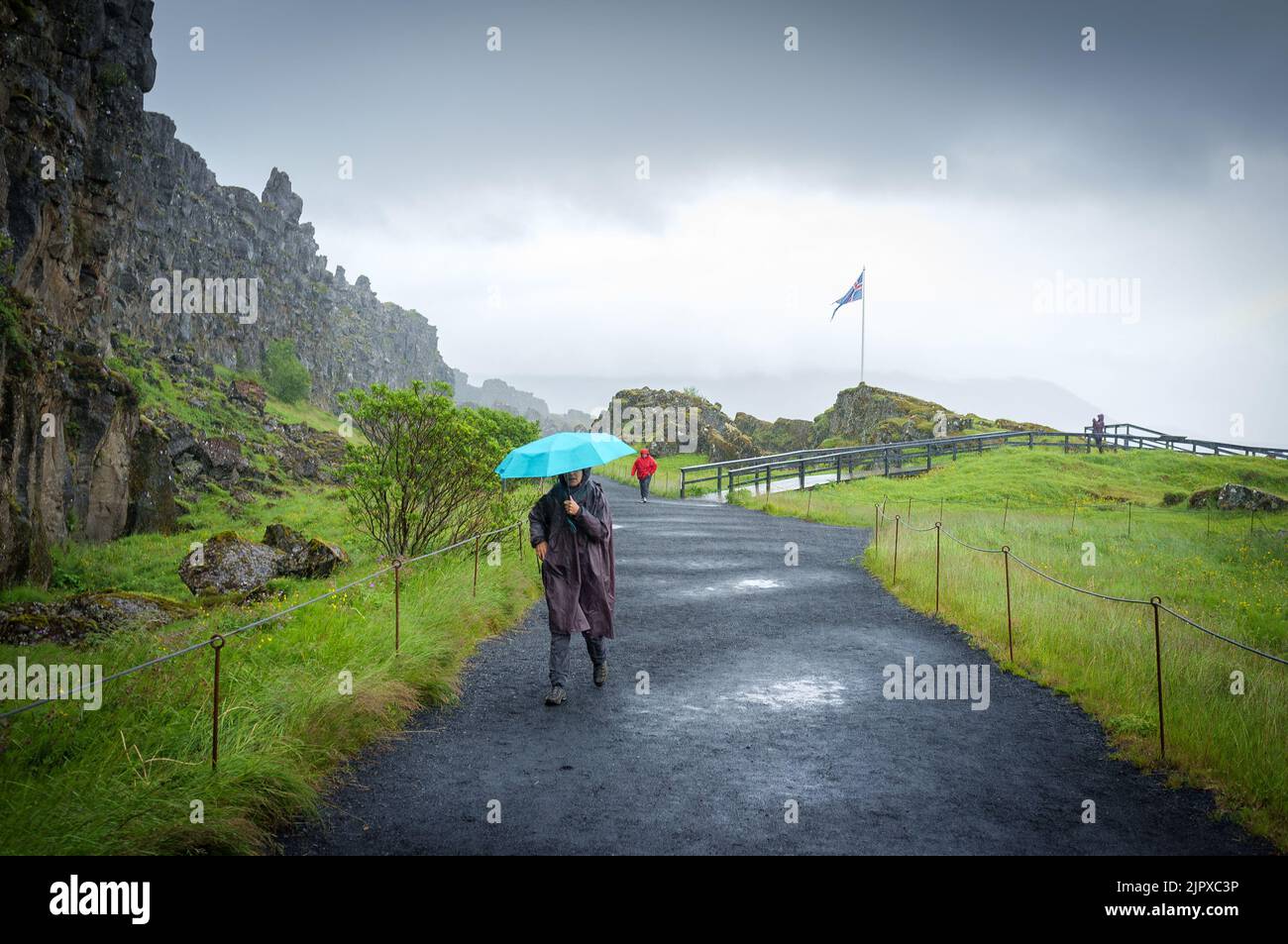 A woman walking with umbrella along a path on a rainy day in ...