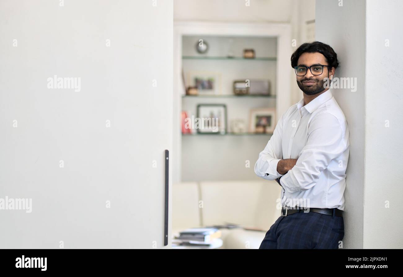 Smiling rich successful young indian business man stands in office ...